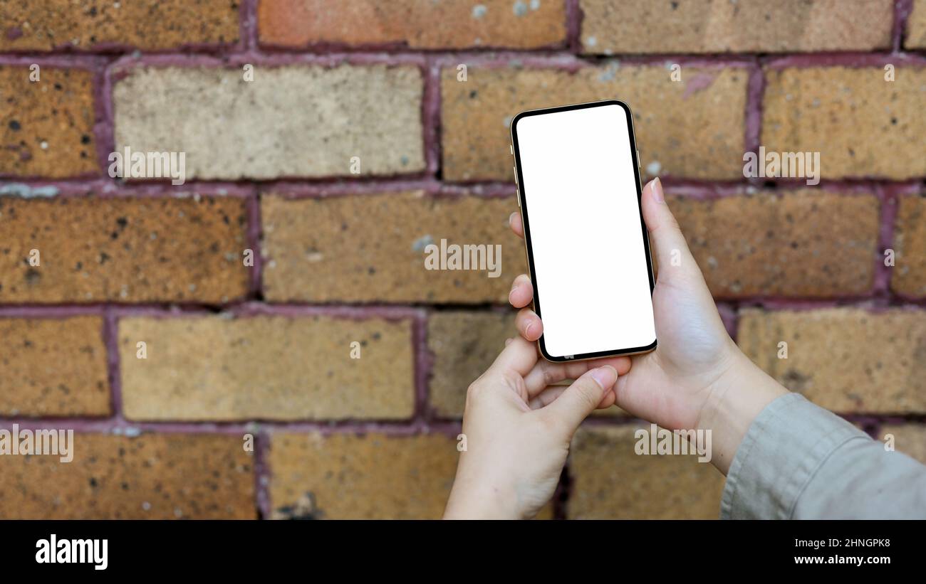 Close-up, Female holding her smartphone over brick wall. Smartphone ...