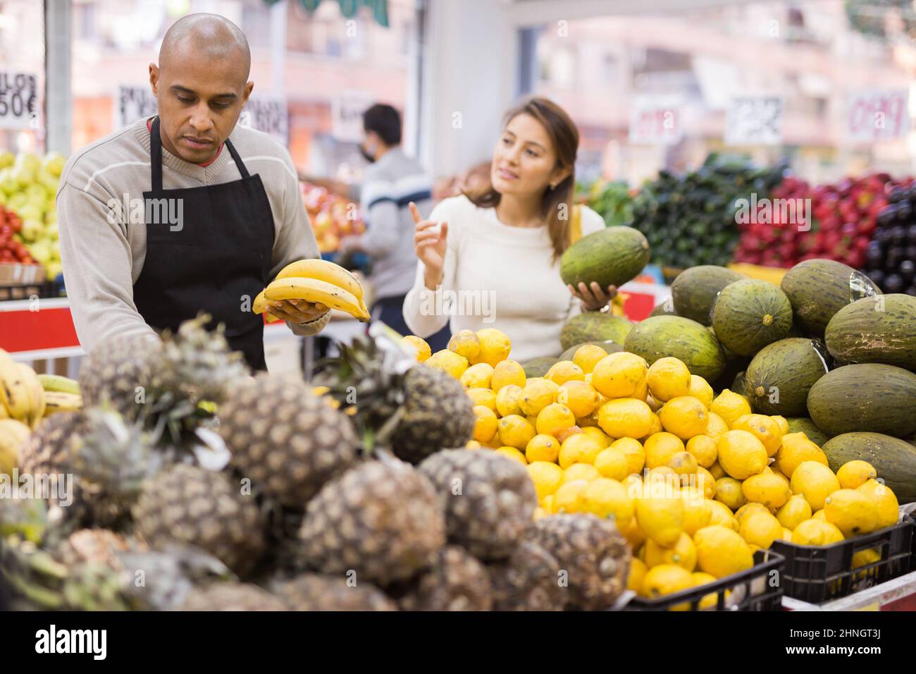 Supermarket worker in black apron stacking fruits Stock Photo - Alamy