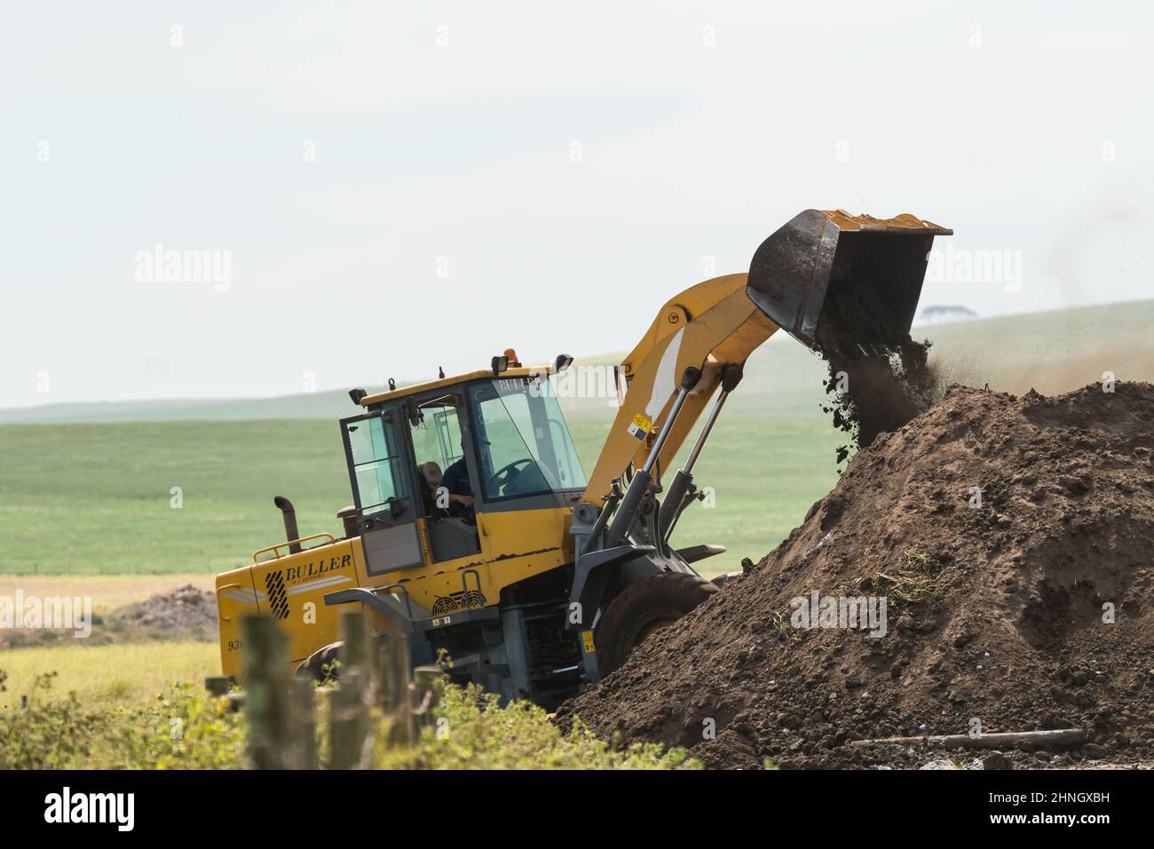 Front end loader or wheel loader heaping earth or sand onto a pile on a ...