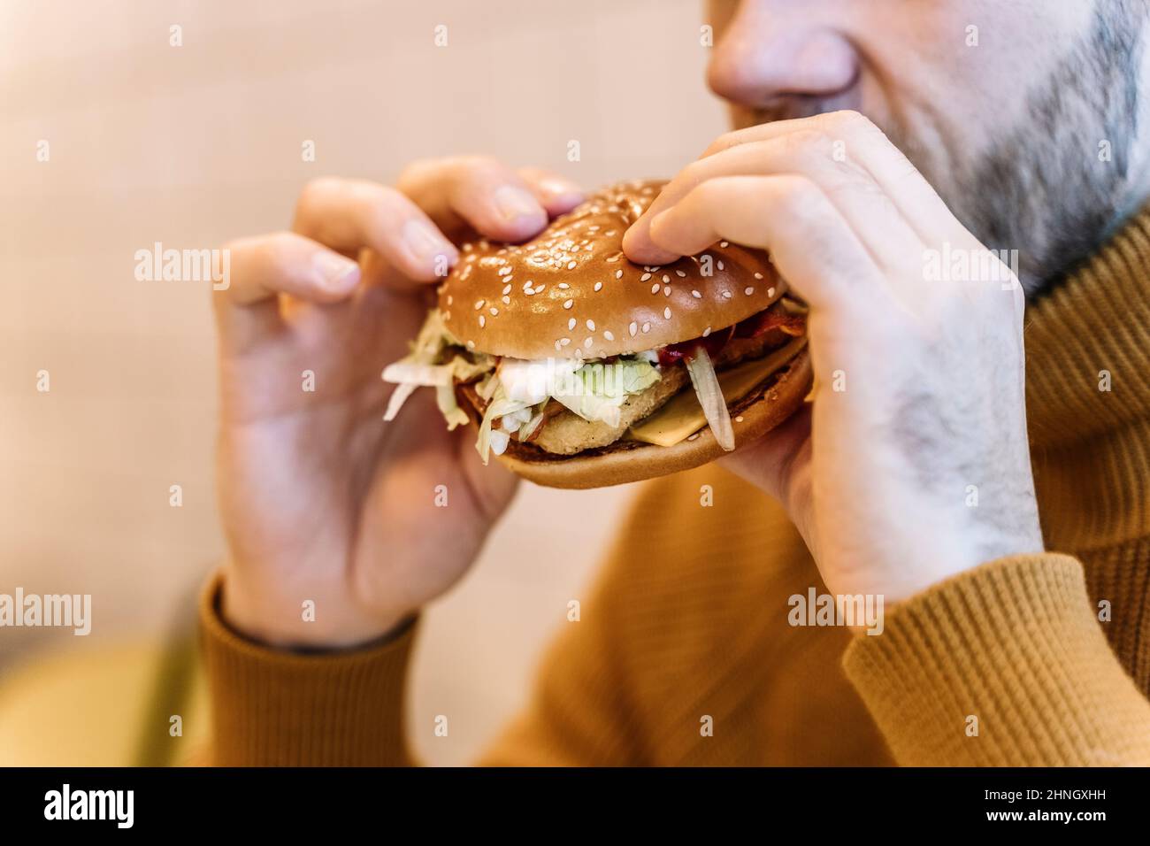 A man eats a burger with meat in a cafe. Fast food, junk food, fast ...