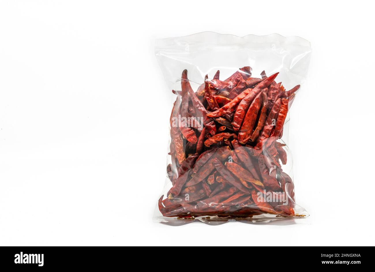 Dried chilli in cleared plastic packaging for sale on white background ...