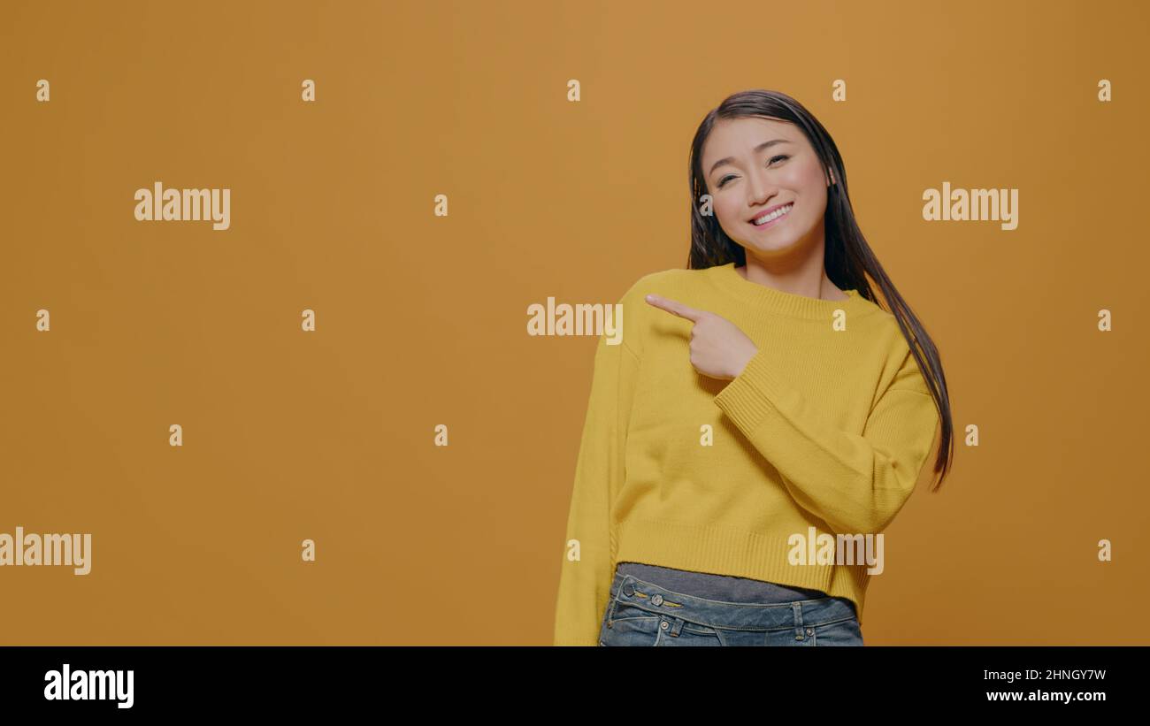 Positive adult pointing at left side of studio in front of camera with ...