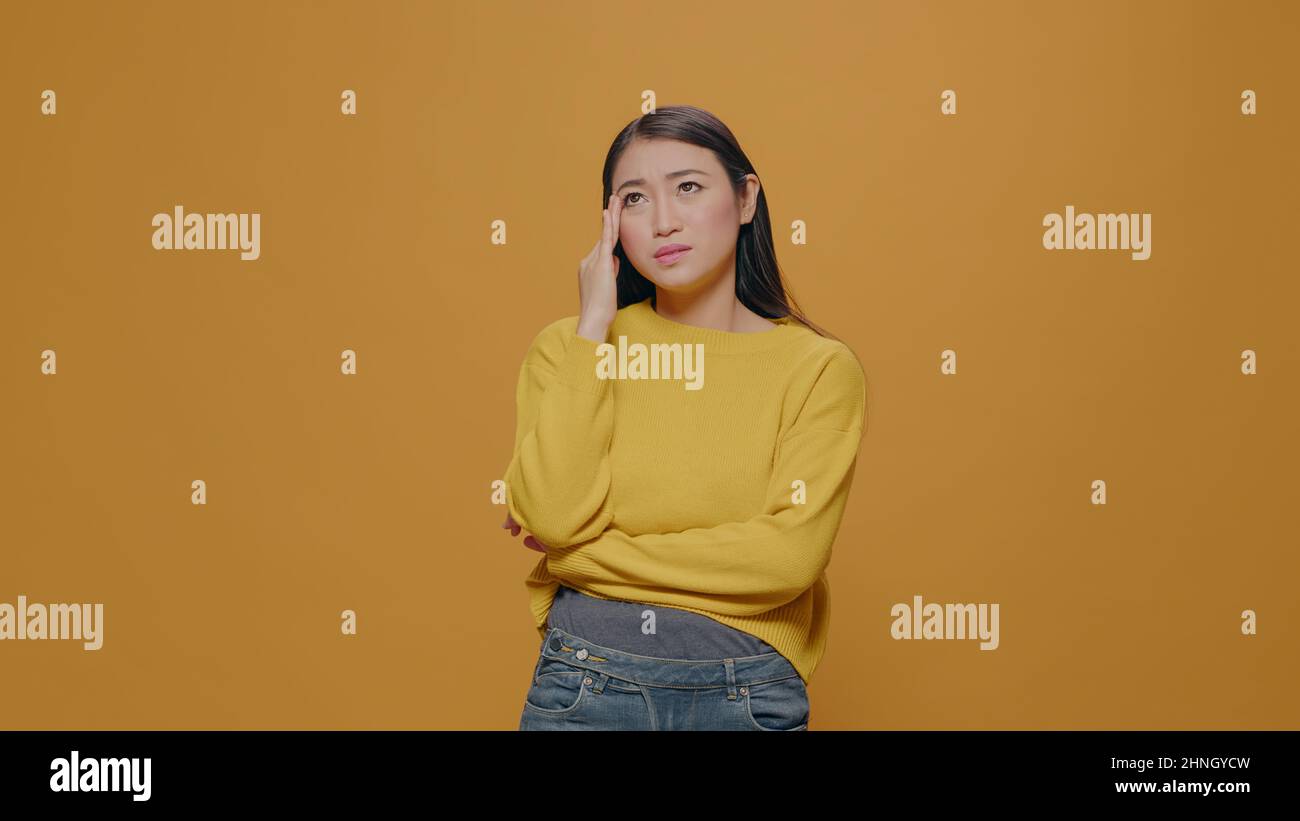 Asian woman feeling worried and emotional on camera in studio. Negative ...