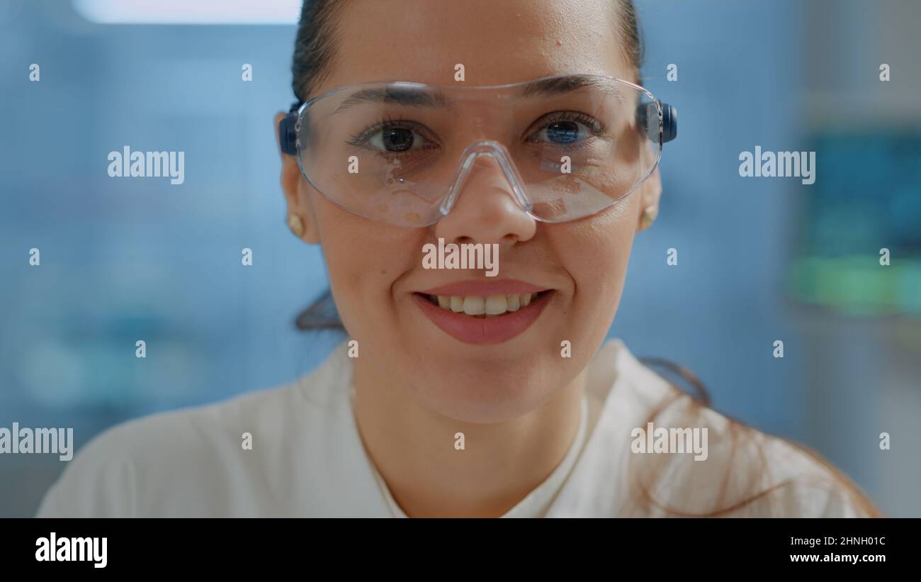 Rack focus of Biologist with safety goggles smiling at camera in ...