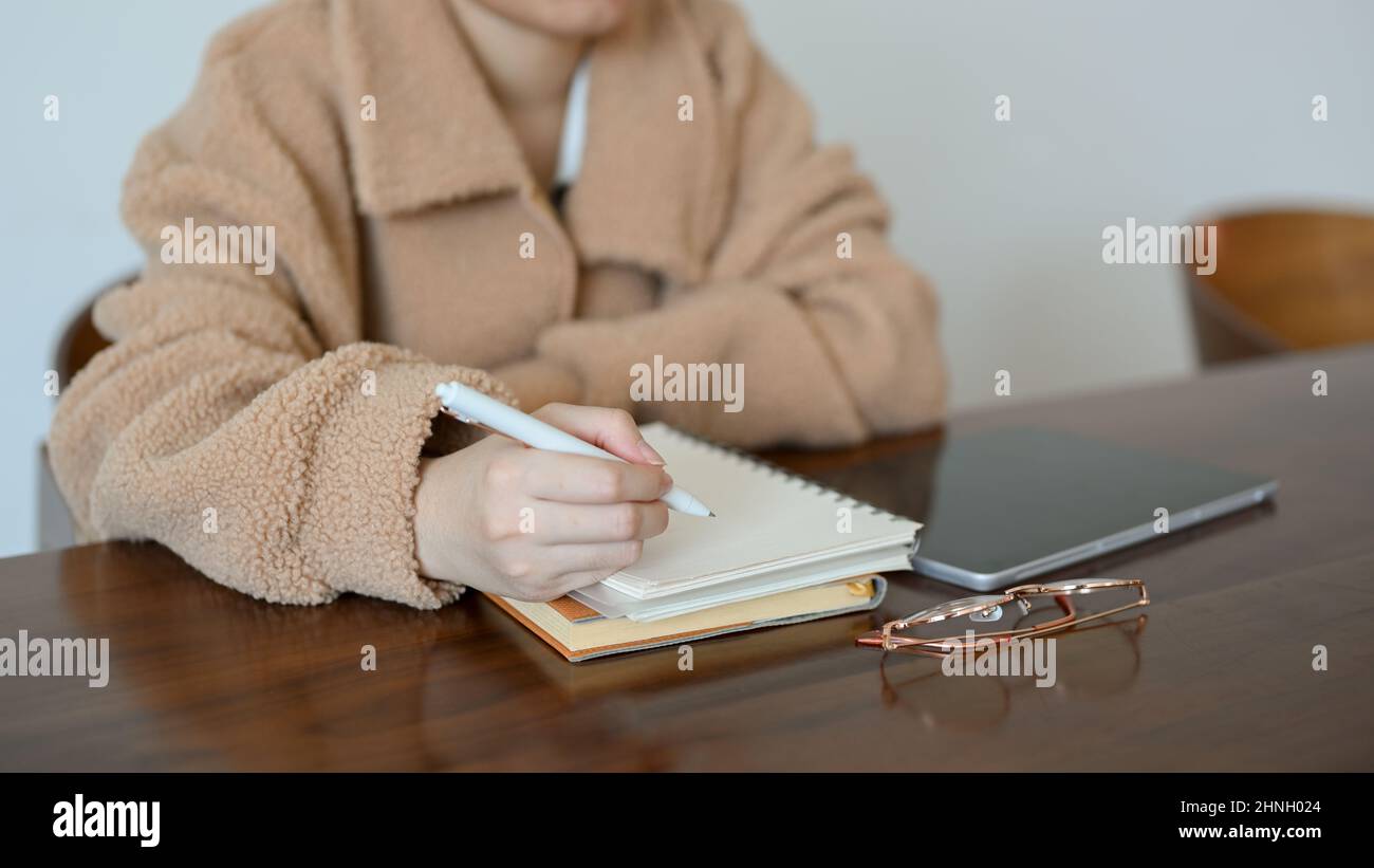 A millennial woman writing down her studying plan in her diary, listing ...