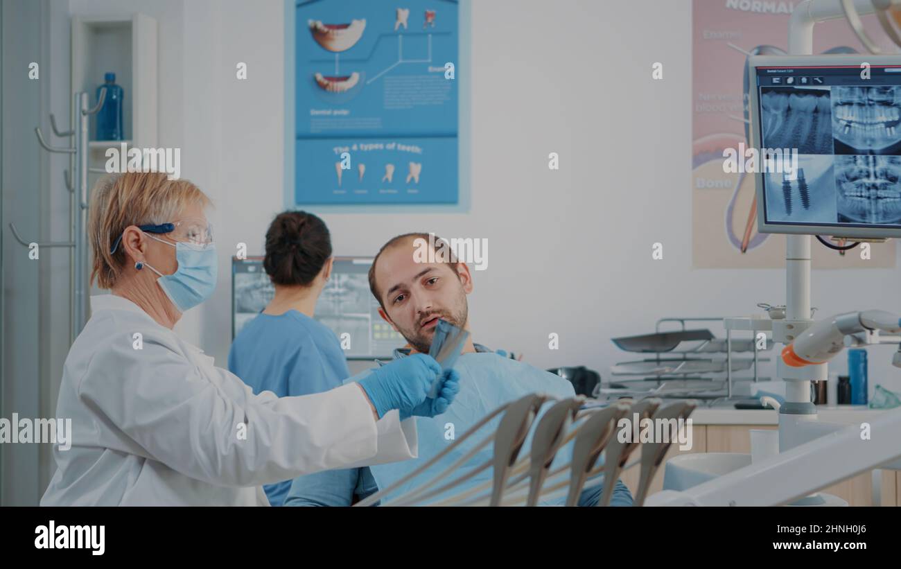 Senior dentist explaining teeth radiography to patient with caries ...
