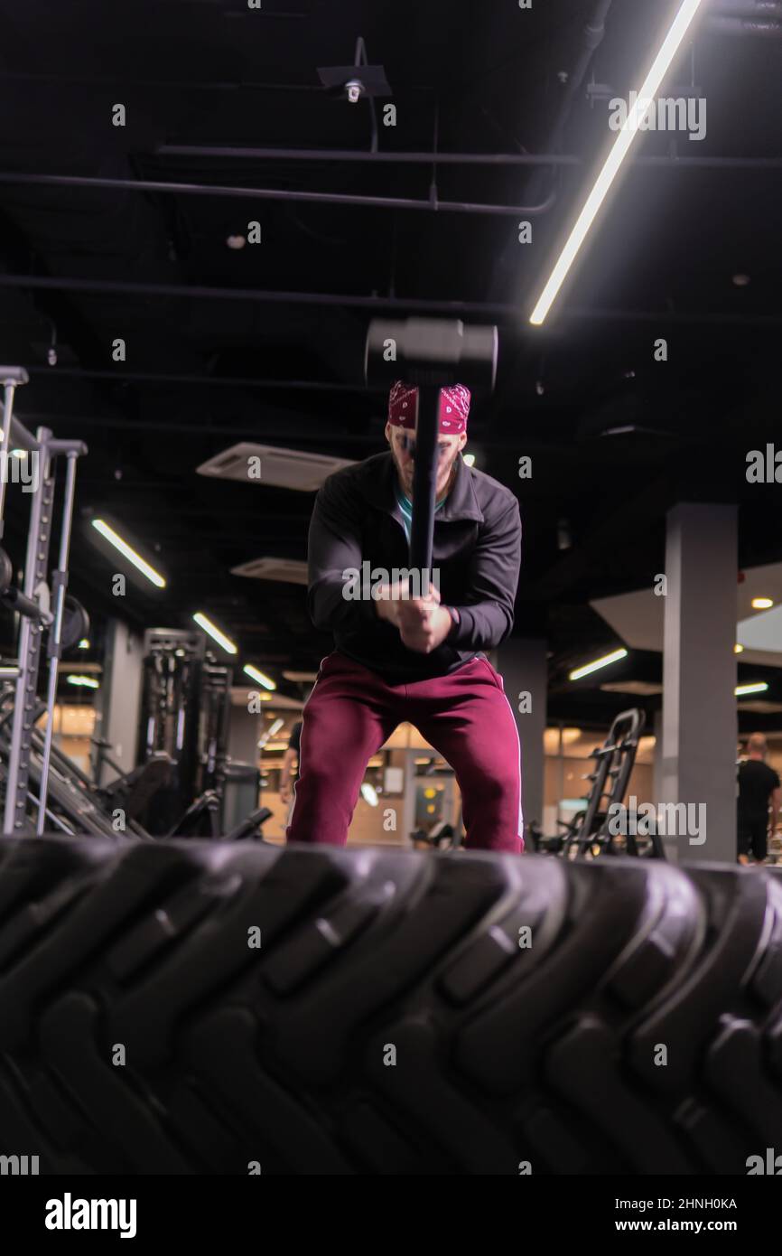 A man hits a sledgehammer wheel in fitness, the concept of a healthy ...