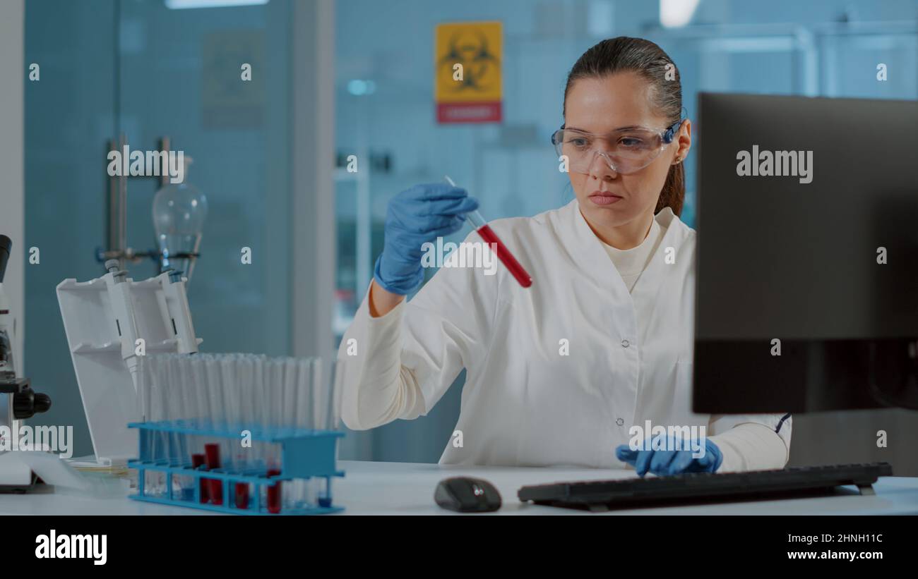 Chemistry researcher looking at substance in test tube for experiment ...