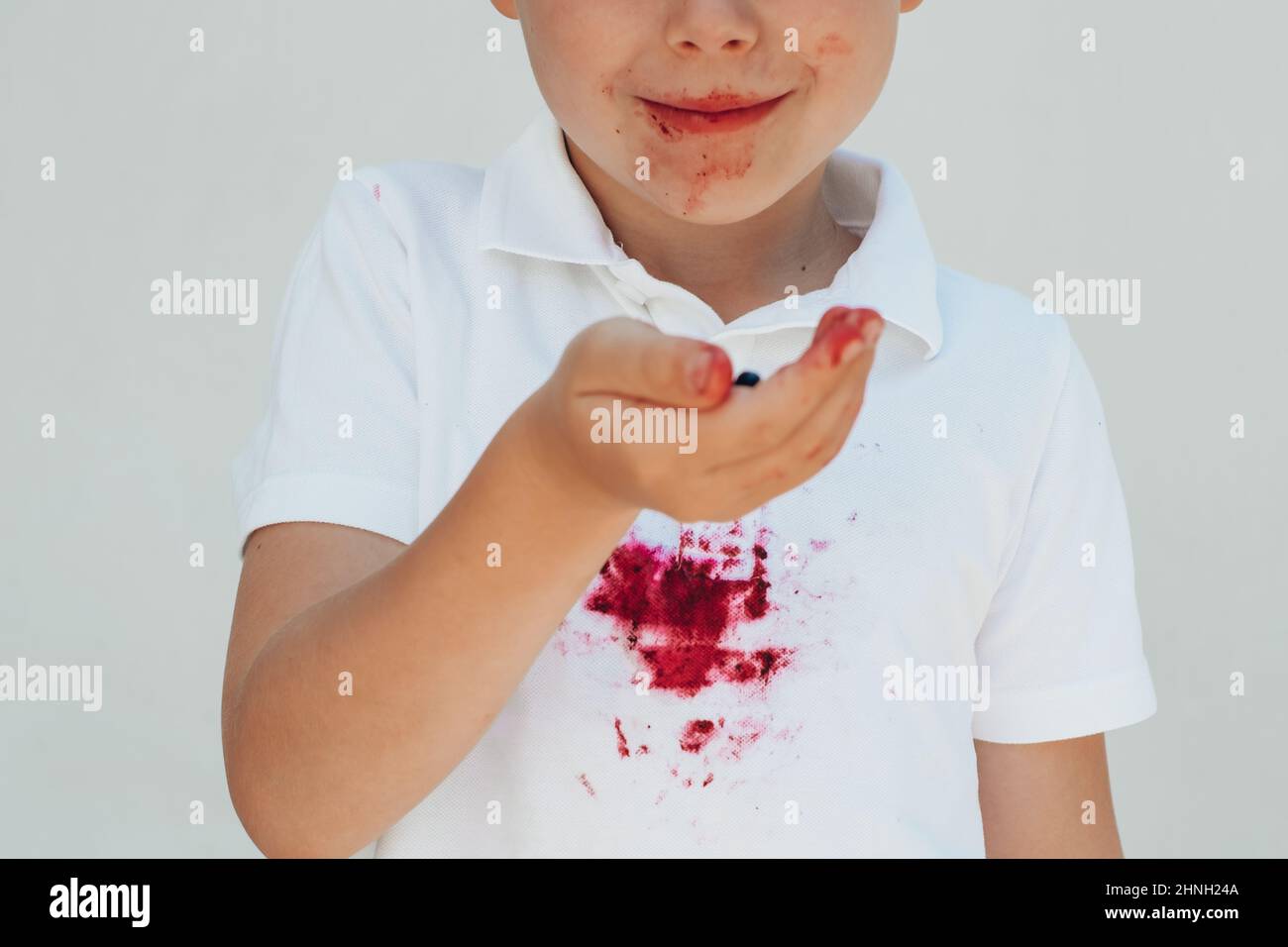 Kid with a dirty face after eating blueberries. dirty stain on a white ...