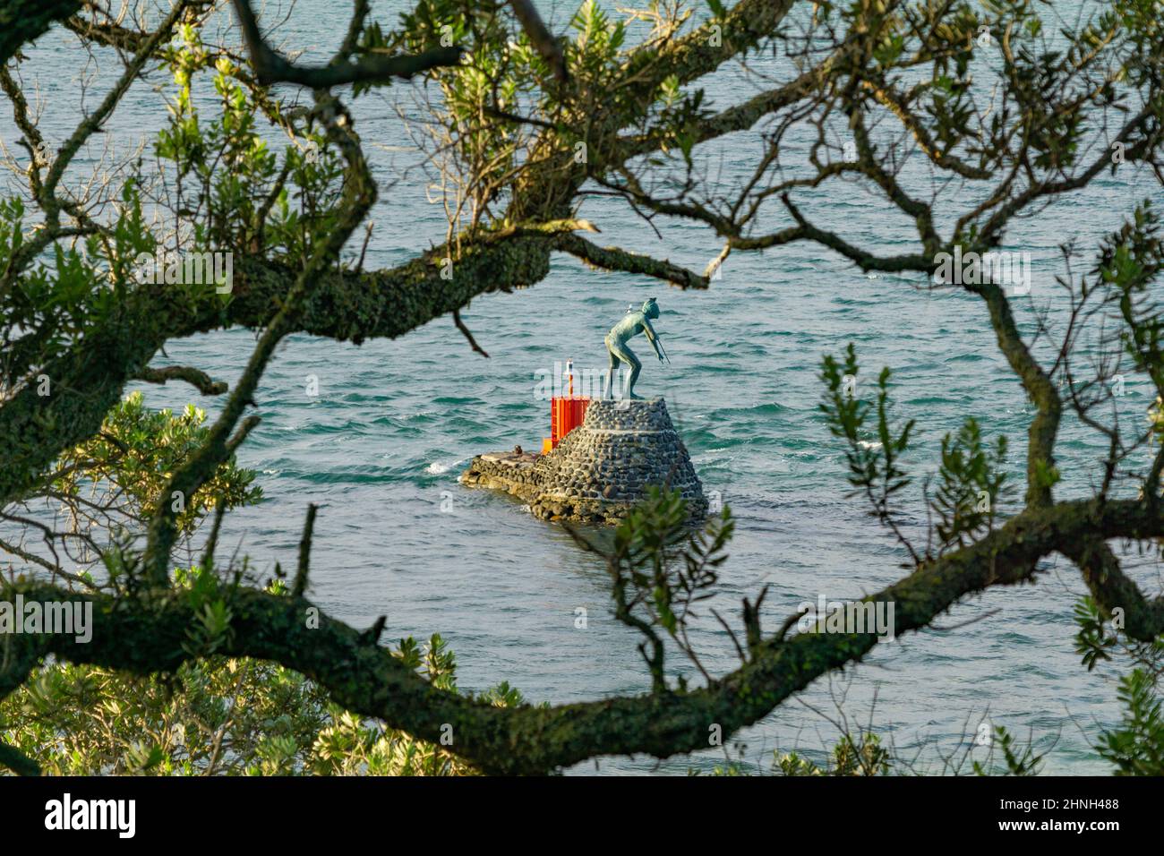 Tangaroa, mythical God of the Seas, statue framed by twisted branches of pohutukawa trees on ...