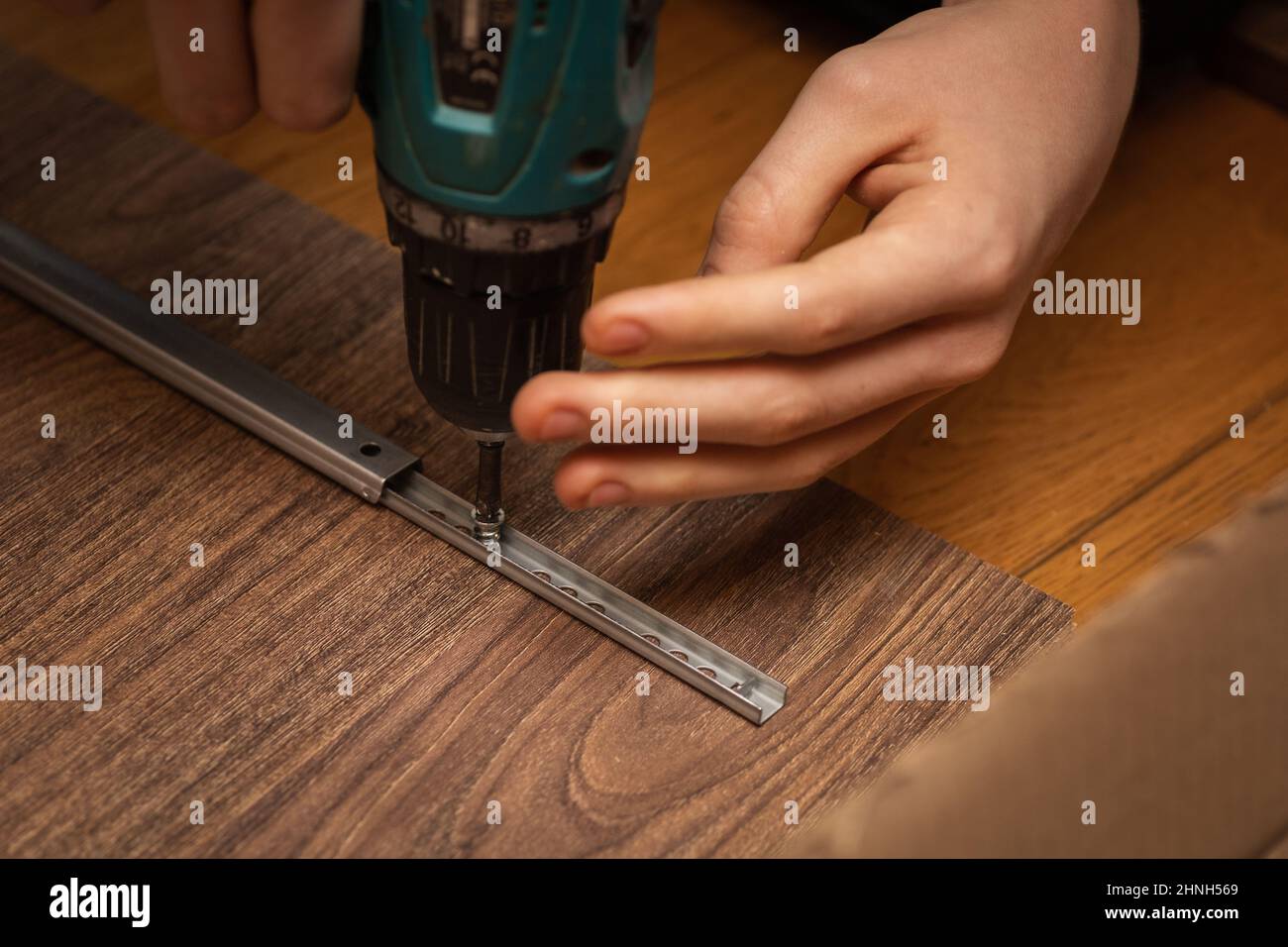 Hands screwing in screws with help of screwdriver to connect iron part ...