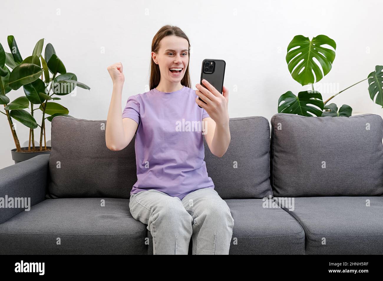 Excited happy woman winner looking at mobile phone using app celebrating success concept ...