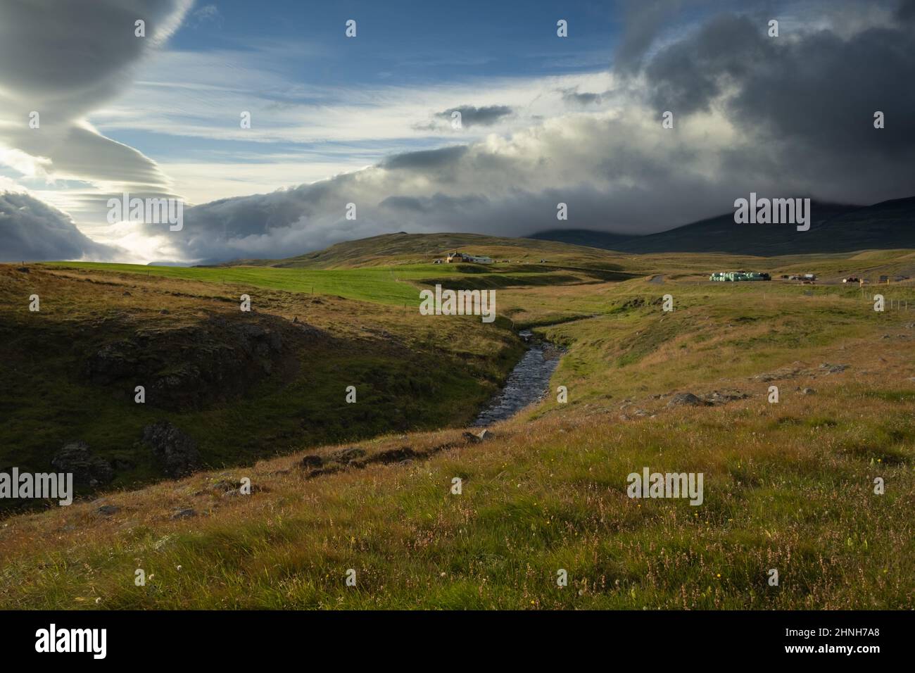 Rain and storm clouds approaching the farmhouse in a wide sunny valley ...