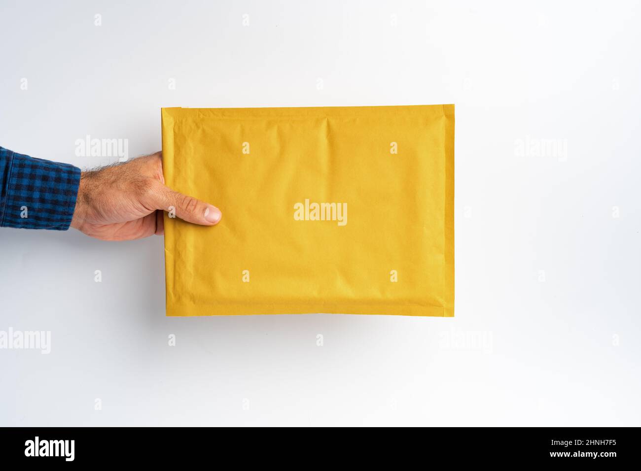 Male hand holding parcel post against white background Stock Photo - Alamy
