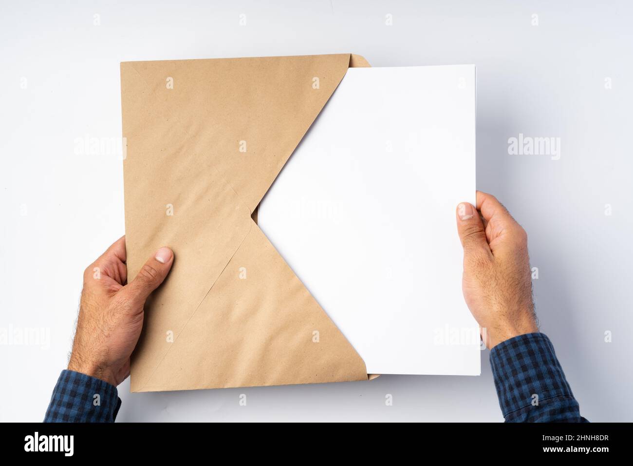 Male hands opening craft paper envelope above white surface Stock Photo ...