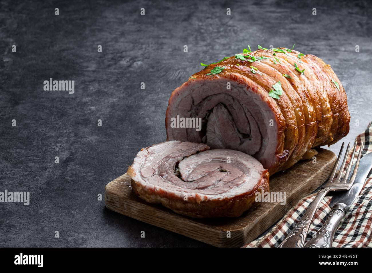 Sliced roast pork meat roll with herbs and spices on gray stone ...
