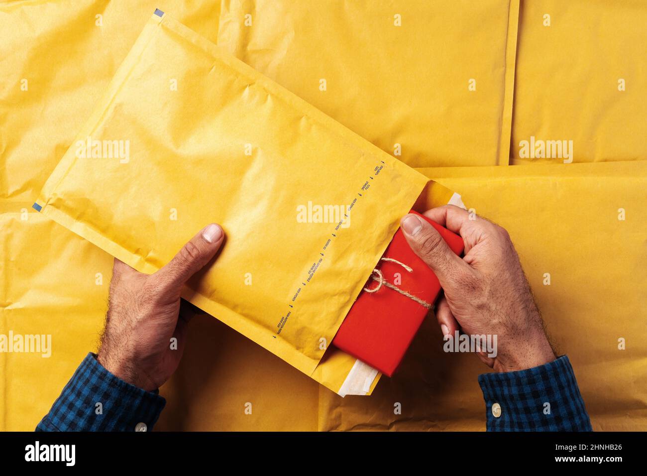 Male hands packing yellow bubble envelopes for shipping Stock Photo - Alamy