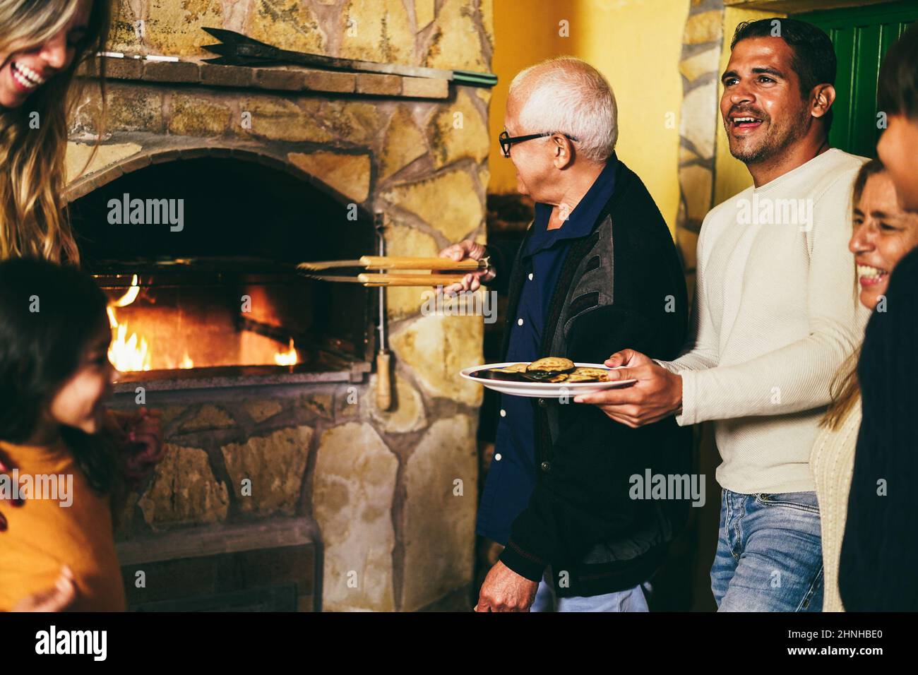 Happy latin family cooking together on wood bbq fireplace - Focus on ...