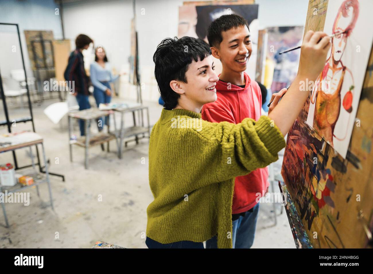 Multiracial students painting inside art room class at school - Focus ...