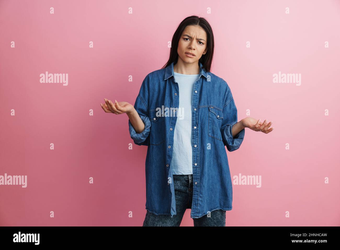 Young hispanic displeased woman holding copyspace and frowning isolated ...