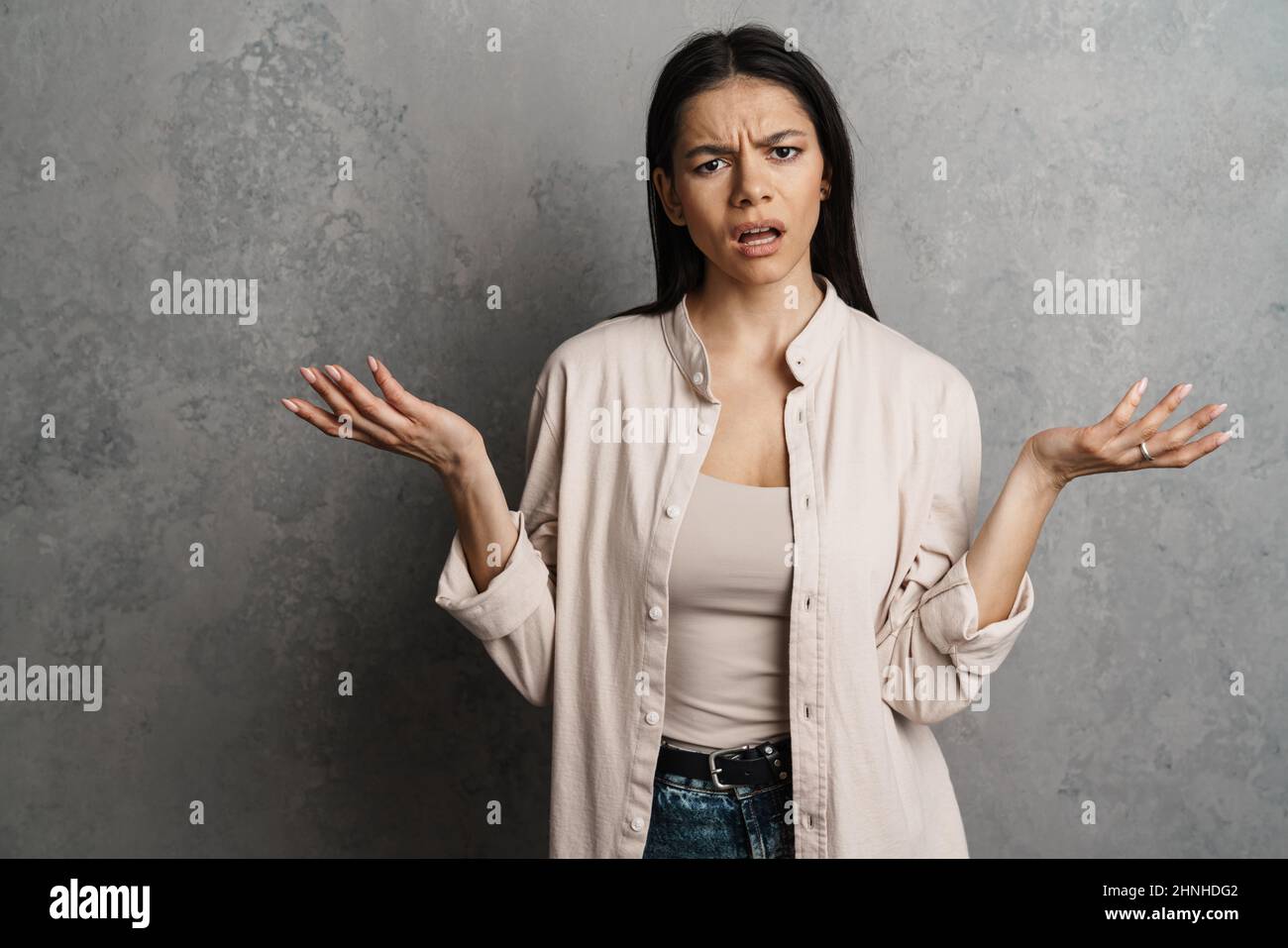 Young hispanic woman frowning and gesturing at camera isolated grey ...
