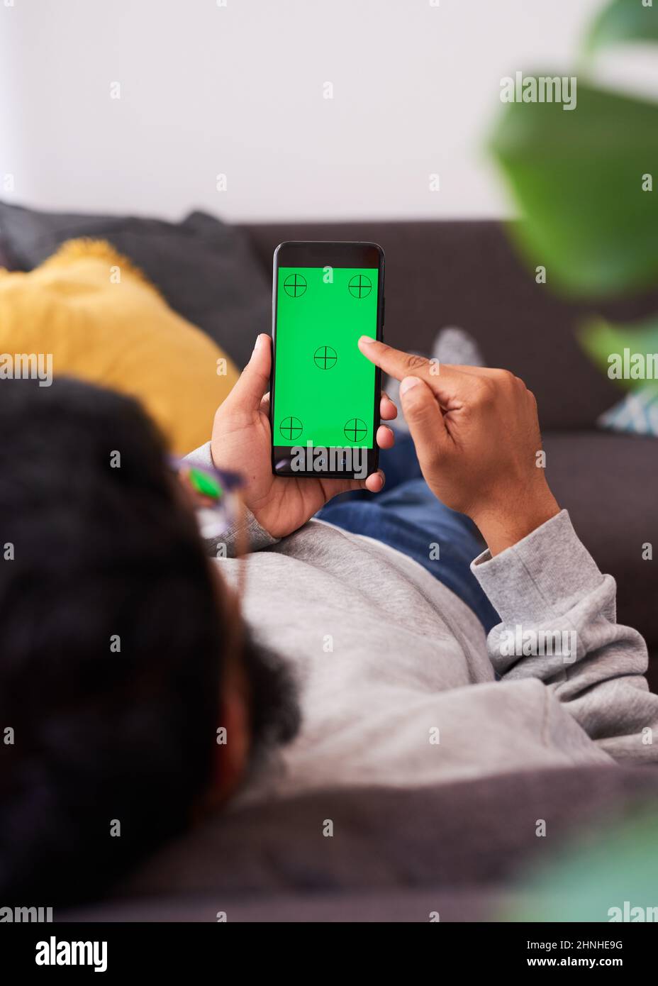 A close up shot of a man scrolling on his mobile phone with a green ...