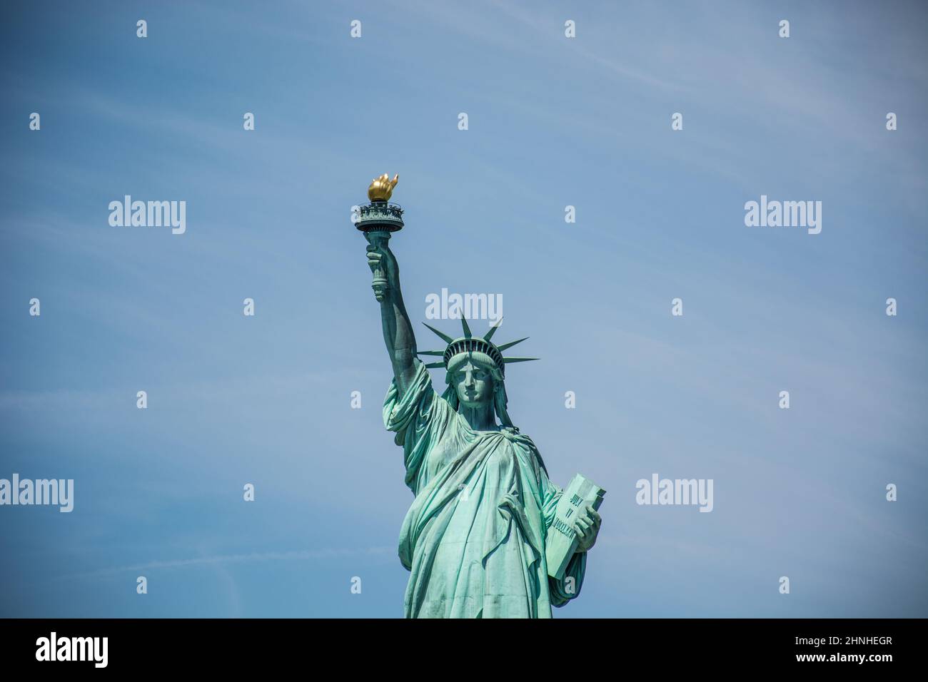 portrait of the statue of liberty with a slightly hazy blue sky and ...