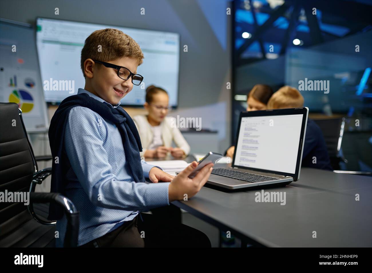 Little businessman checking cellphone during office meeting Stock Photo ...