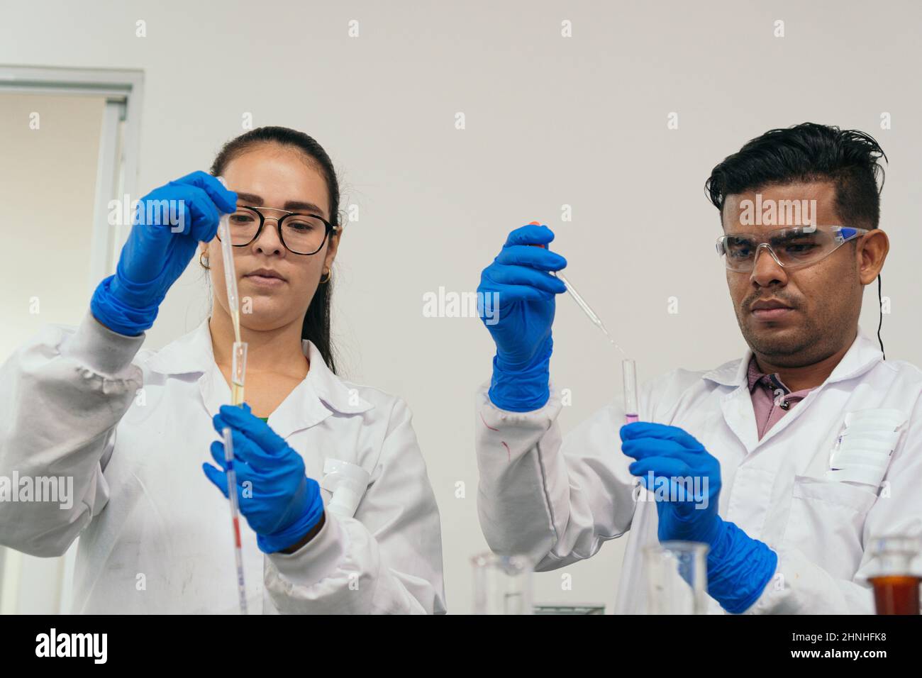 Laboratory technicians performing chemical tests. Scientists wearing ...