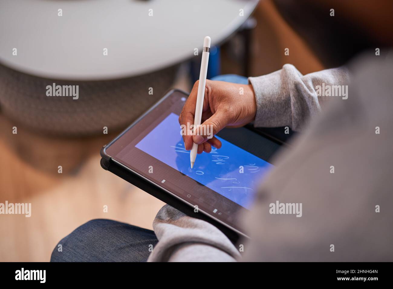 A close up shot of a man's hands using a stylus to draw on a tablet ...