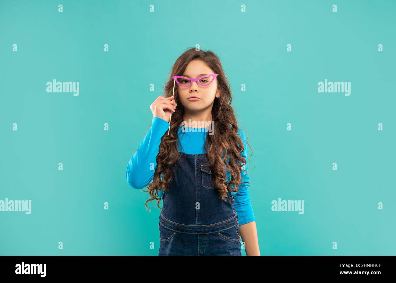 arrogant kid with long curly hair on blue background. funny child with ...