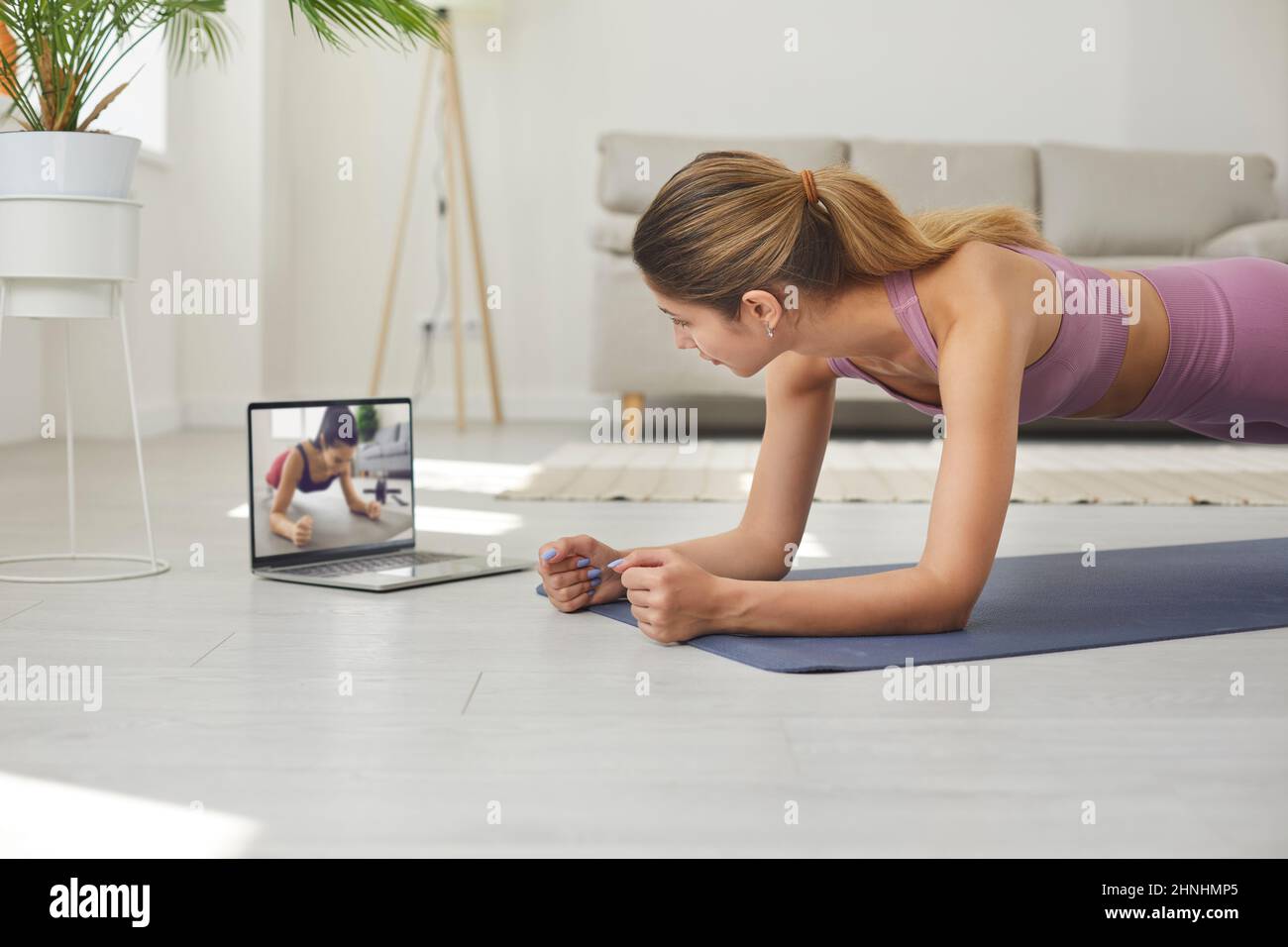 Woman doing plank exercise during her home workout with remote fitness ...