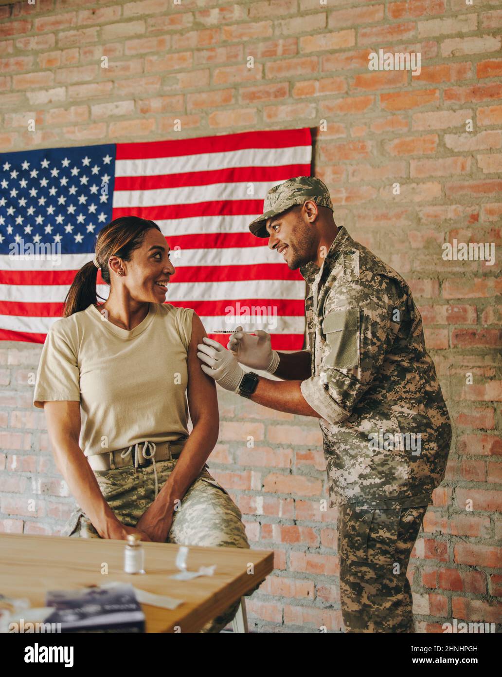 Smiling military doctor inoculating a female soldier during the ...