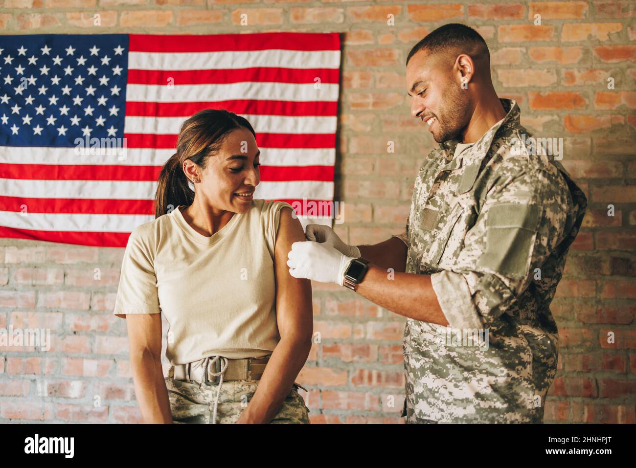 Happy military nurse placing a bandage on a soldier's arm in the ...