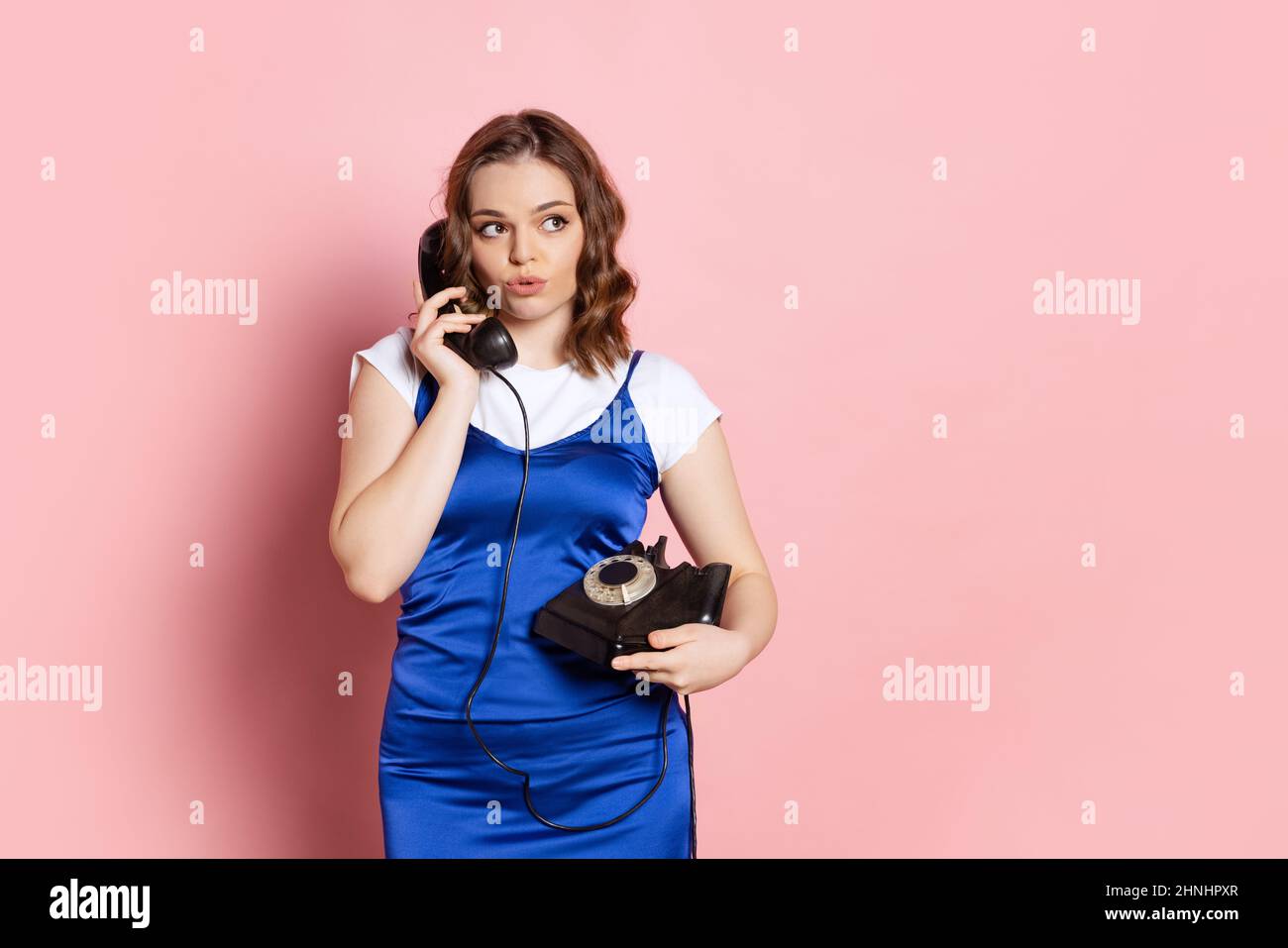 Portrait of young girl wearing retro style attire using vintage phone ...
