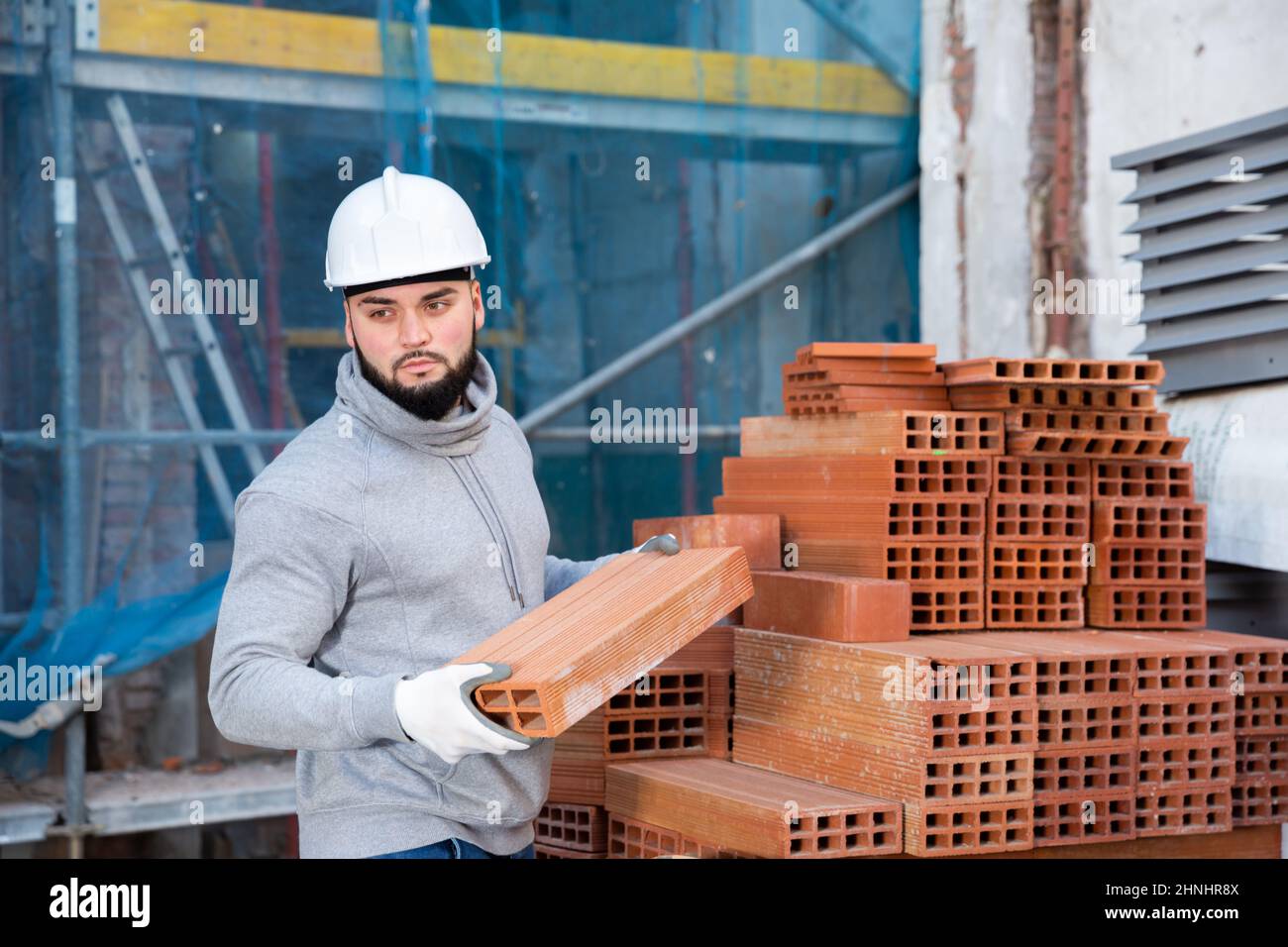 Bricklayer taking red bricks from stack Stock Photo - Alamy