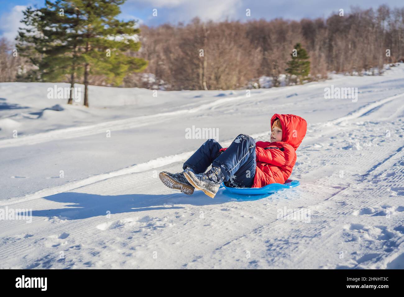 happy and positive little boy enjoying sledding and cold weather ...