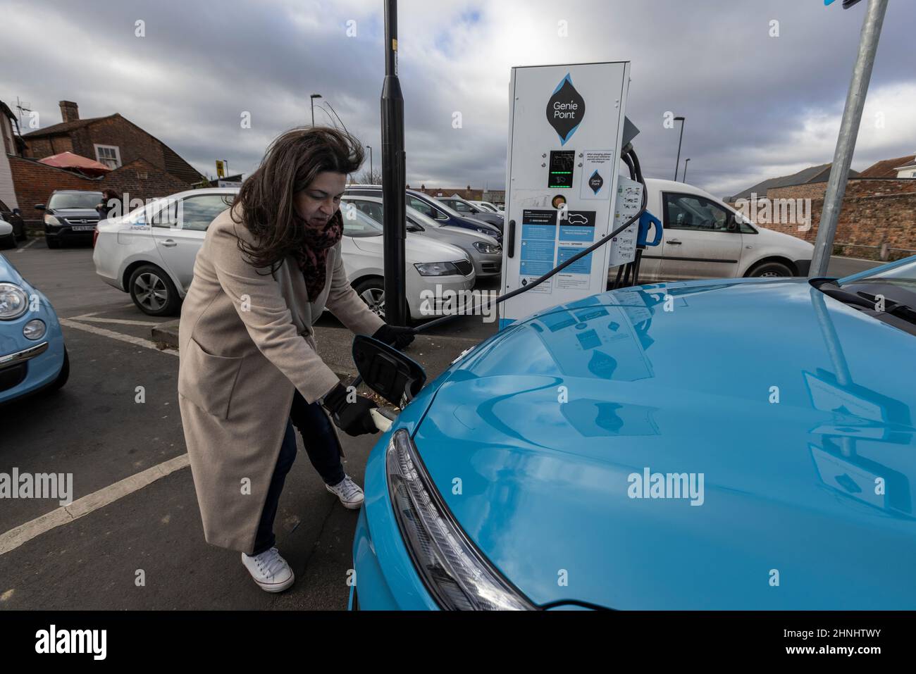 Middle aged lady using 'GeniePoint EV Charging' vehicle charging point ...