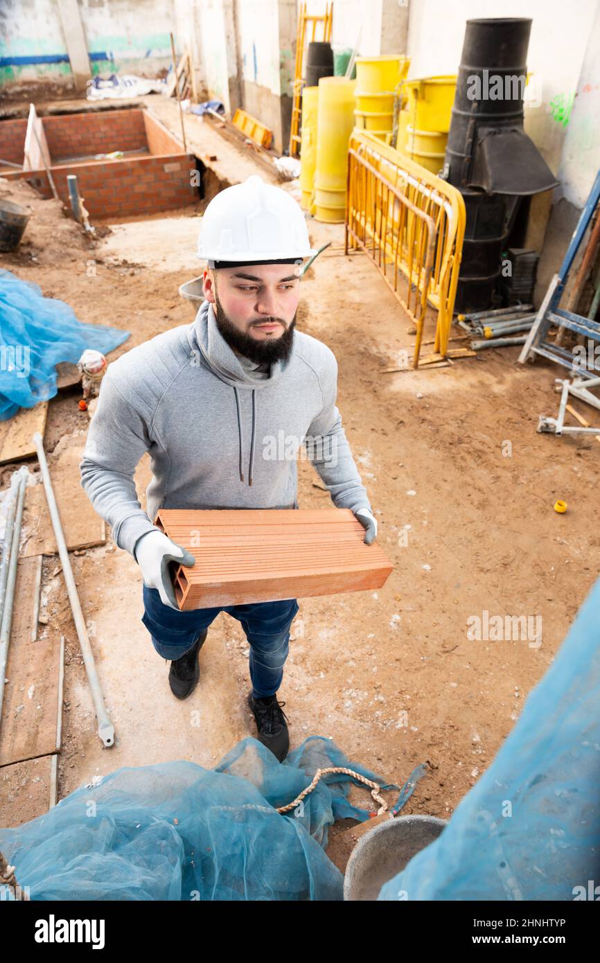 Builder working with red brick Stock Photo - Alamy