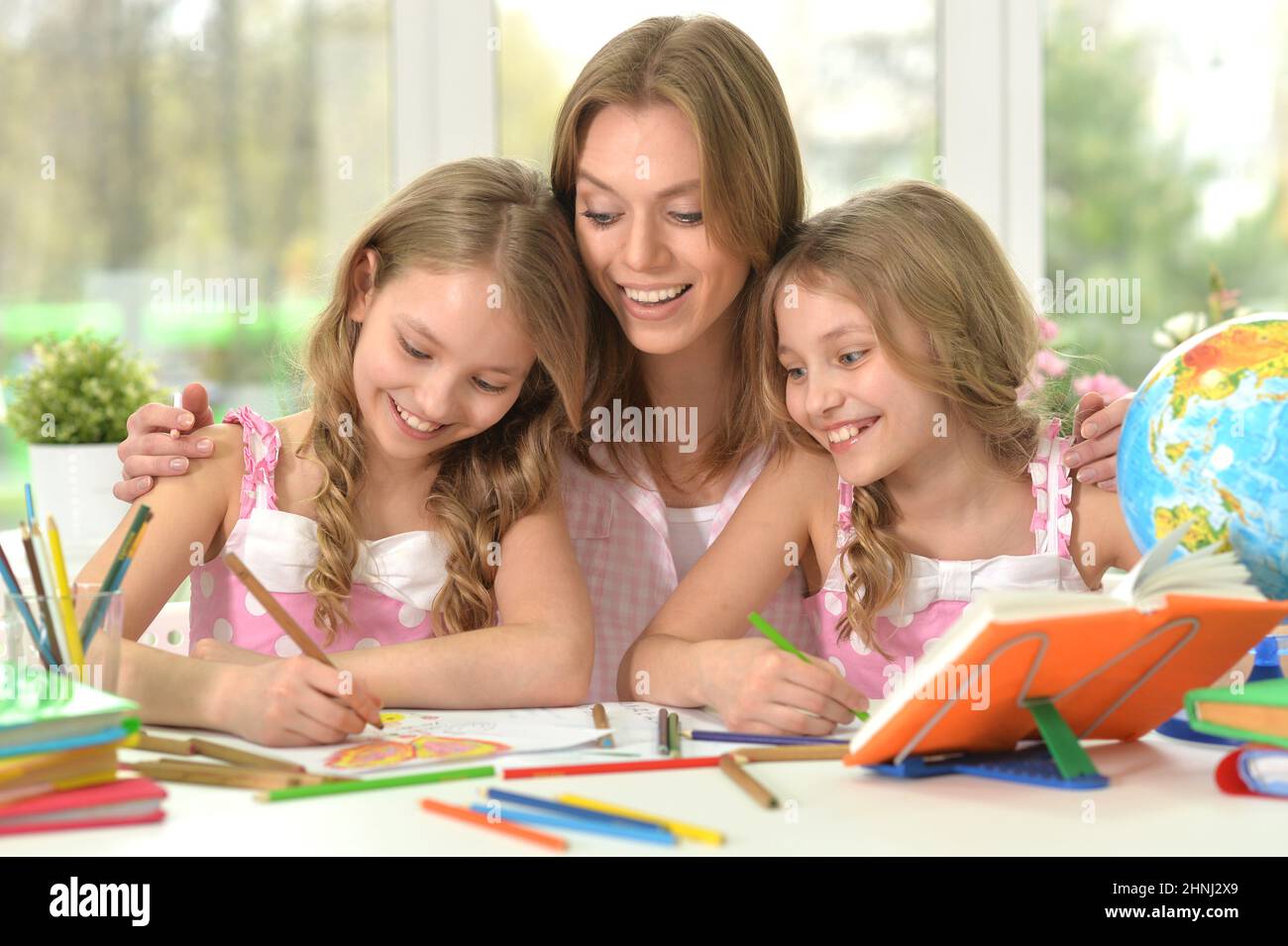 Teacher with two girls drawing together at art class Stock Photo - Alamy
