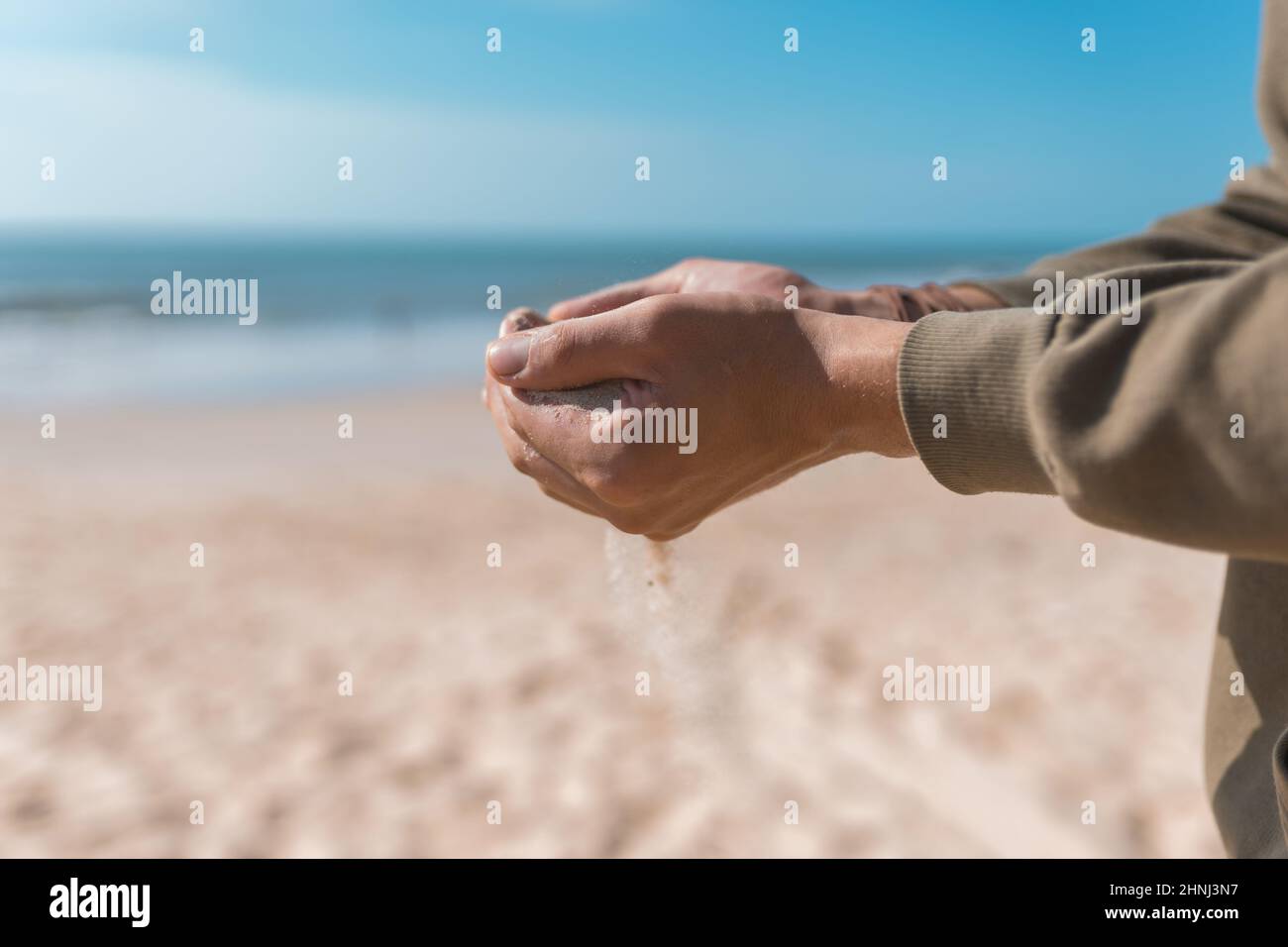 Man holding white sand in his hands. Male palms with the sand on the ...