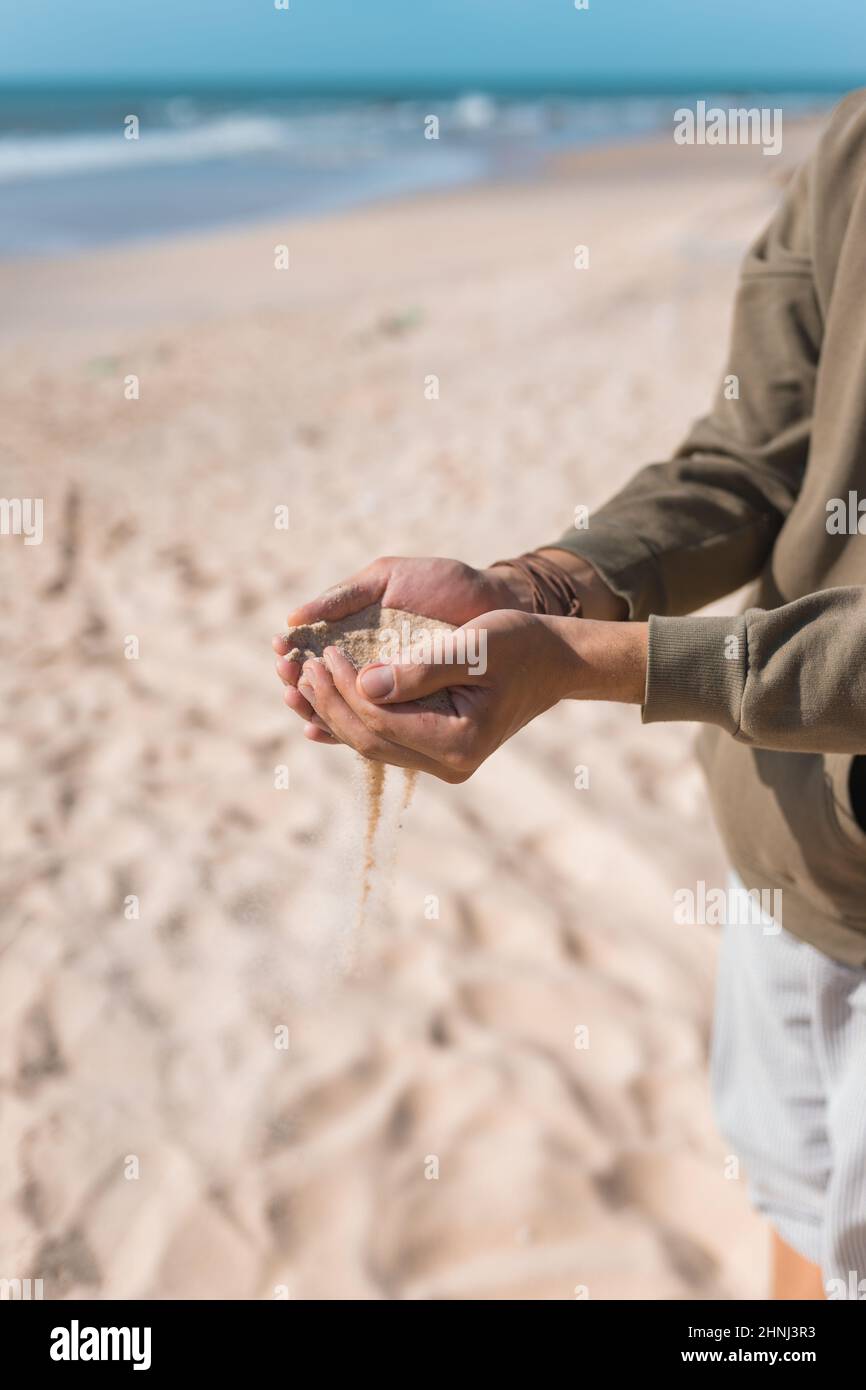 Man holding white sand in his hands. Male palms with the sand on the ...