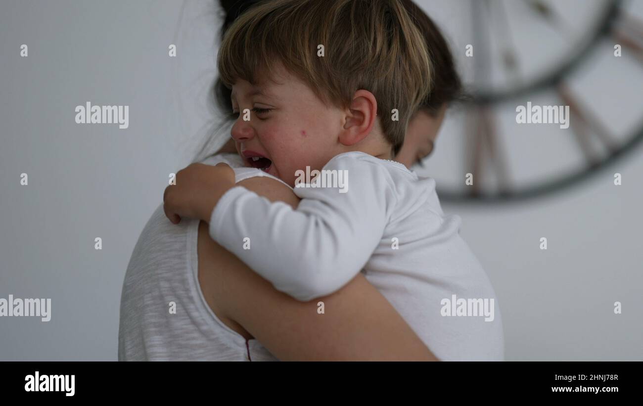 Mother holding tearful child in arm mom and toddler love and affection ...
