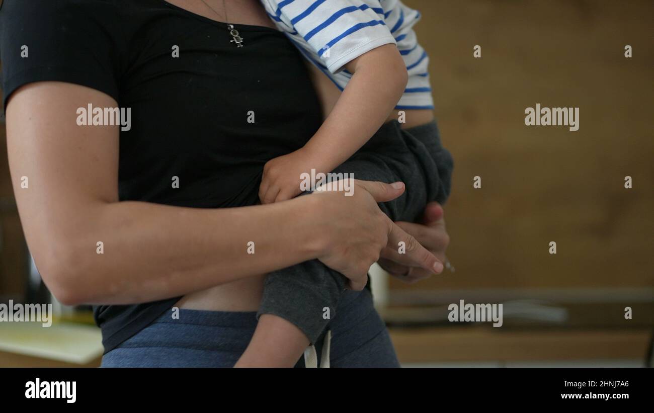 Mother holding child in arms while cooking mom multi-tasking Stock ...