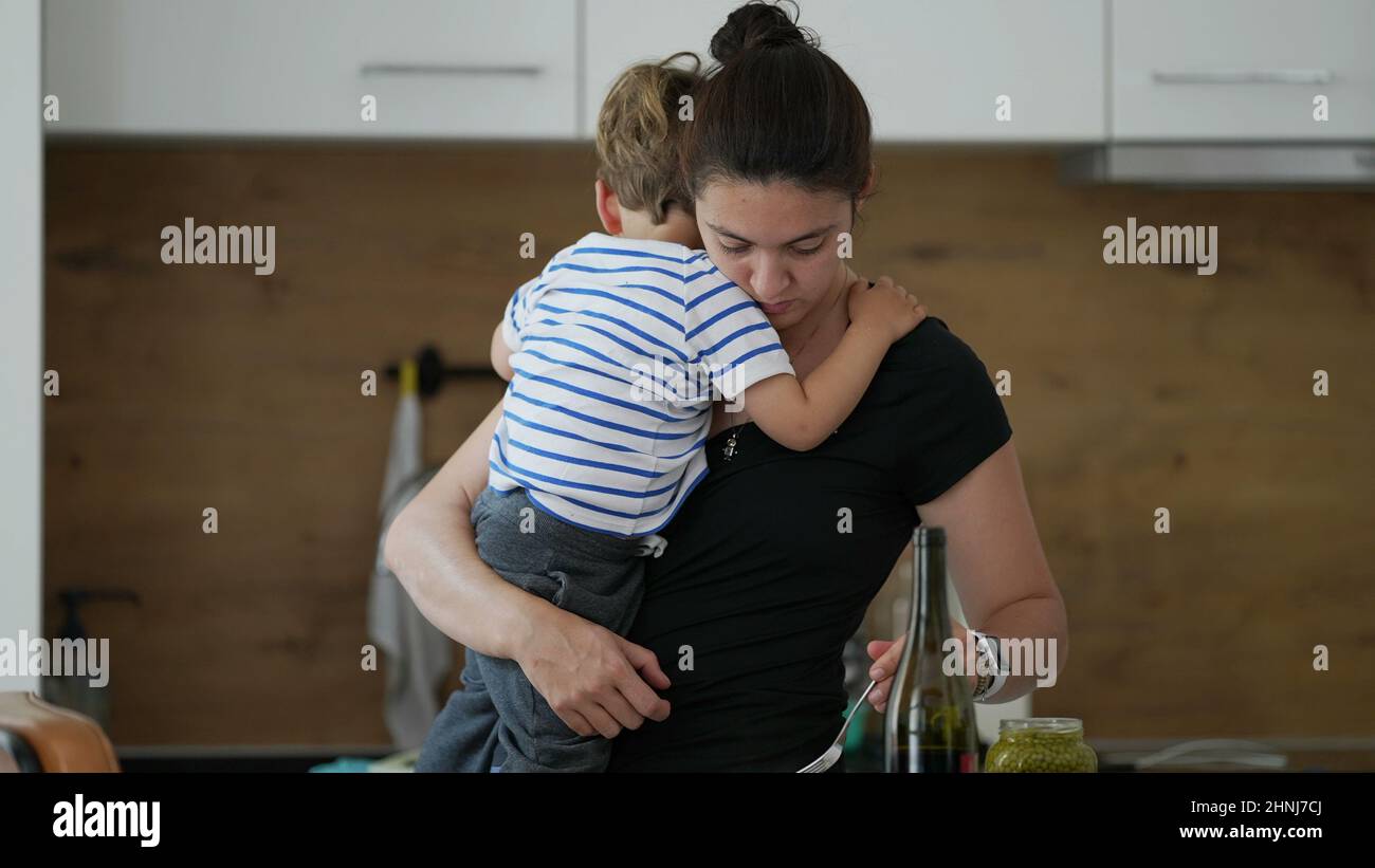 Mother multi-tasking holding child cooking at home Candid authentic and ...
