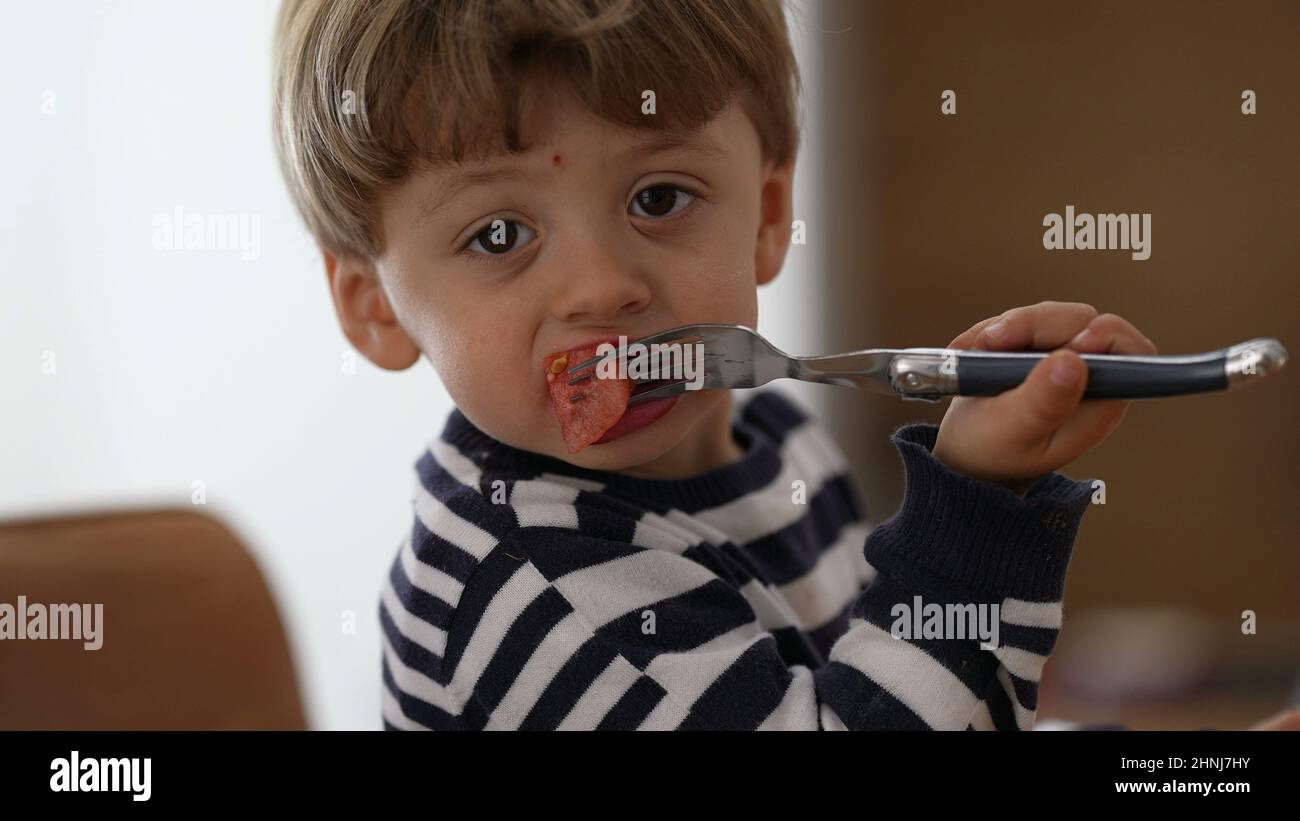 One child eating fruit snack holding fork by himself Stock Photo - Alamy