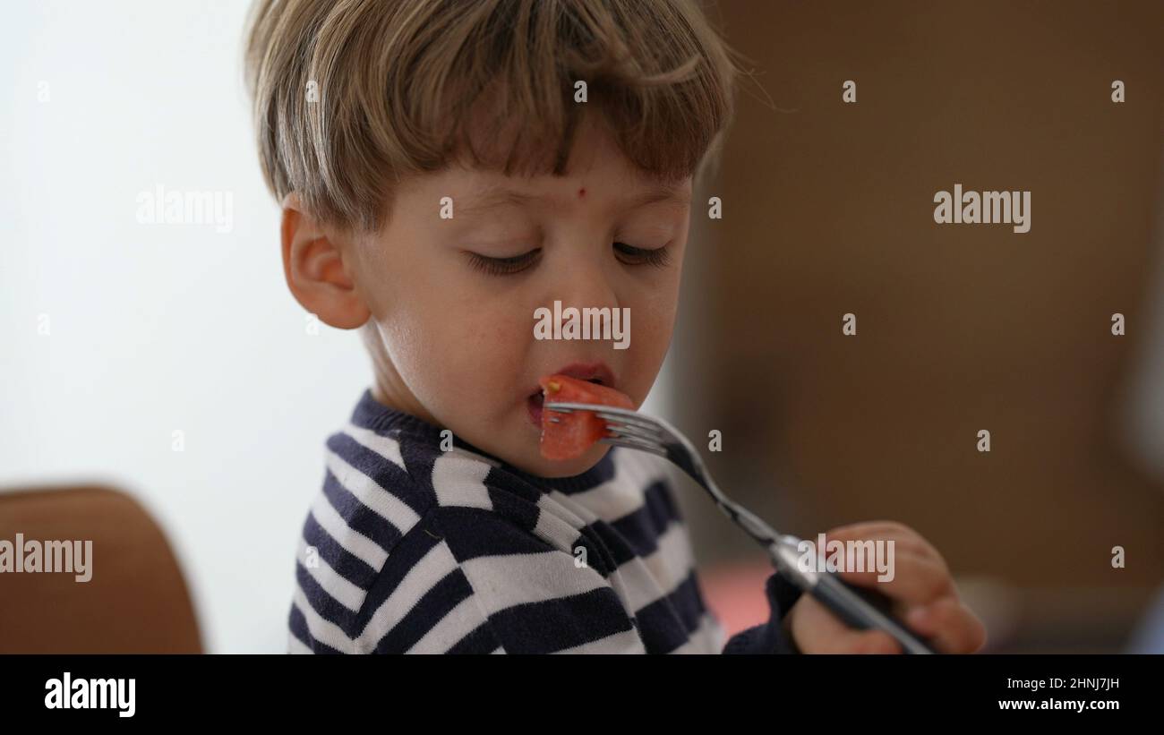 One child eating fruit snack holding fork by himself Stock Photo - Alamy
