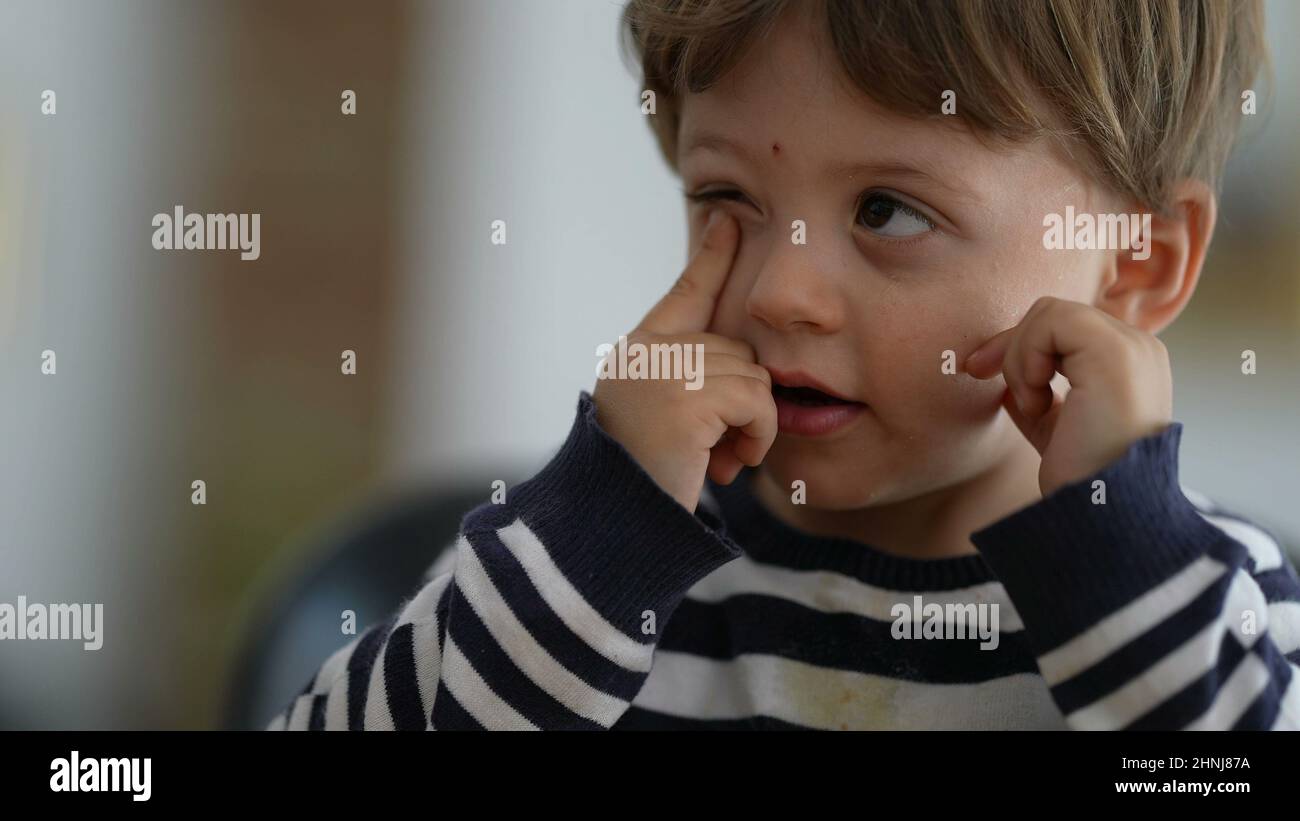 Toddler touching eyes and face with hand child rubbing face with finger ...