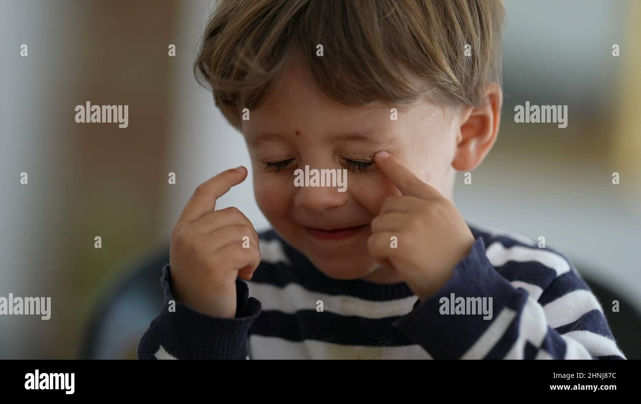 Toddler touching eyes and face with hand child rubbing face with finger ...