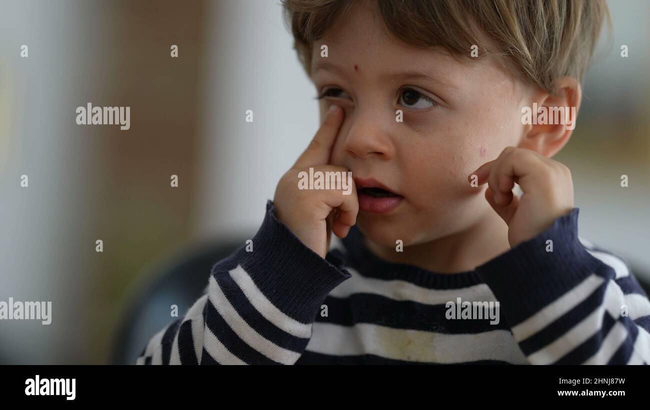Toddler touching eyes and face with hand child rubbing face with finger ...
